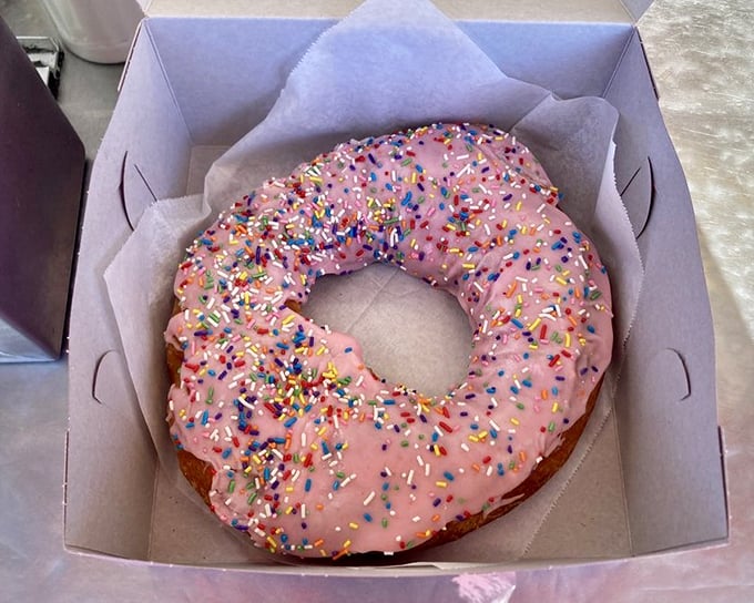 This pink-frosted donut with chocolate drizzle isn't just breakfast&mdash;it's a celebration on a paper napkin. Sprinkles optional, joy mandatory.