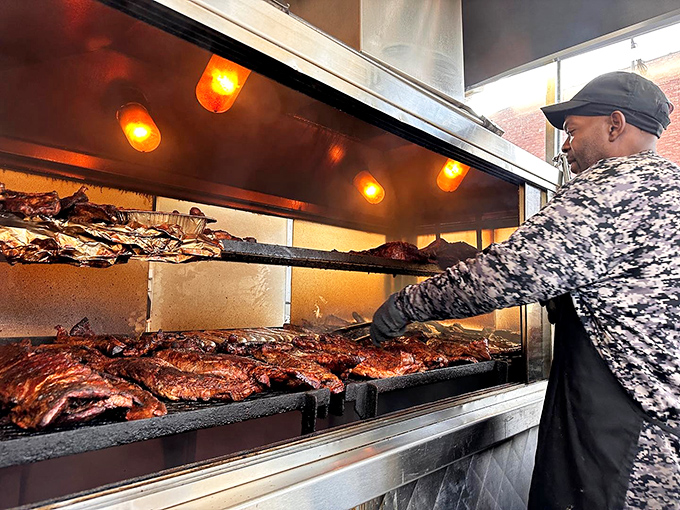 Behind the glass, the pitmaster orchestrates a smoky ballet, moving meat with the precision and confidence of someone who's mastered their craft.