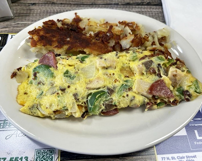 An omelet that's practically bursting with fillings, paired with crispy hash browns. This isn't breakfast&mdash;it's a celebration on a plate.