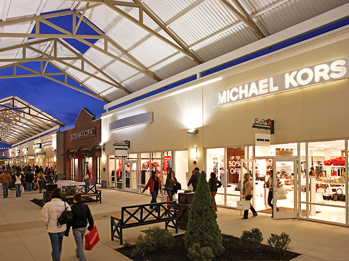 As night falls, Michael Kors glows with promise, those 50% off signs in the window working better than any North Star to guide dedicated shoppers home. 