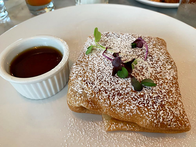 This pastry looks like it's wearing a powdered sugar snow coat, ready for its close-up with that side of maple syrup.
