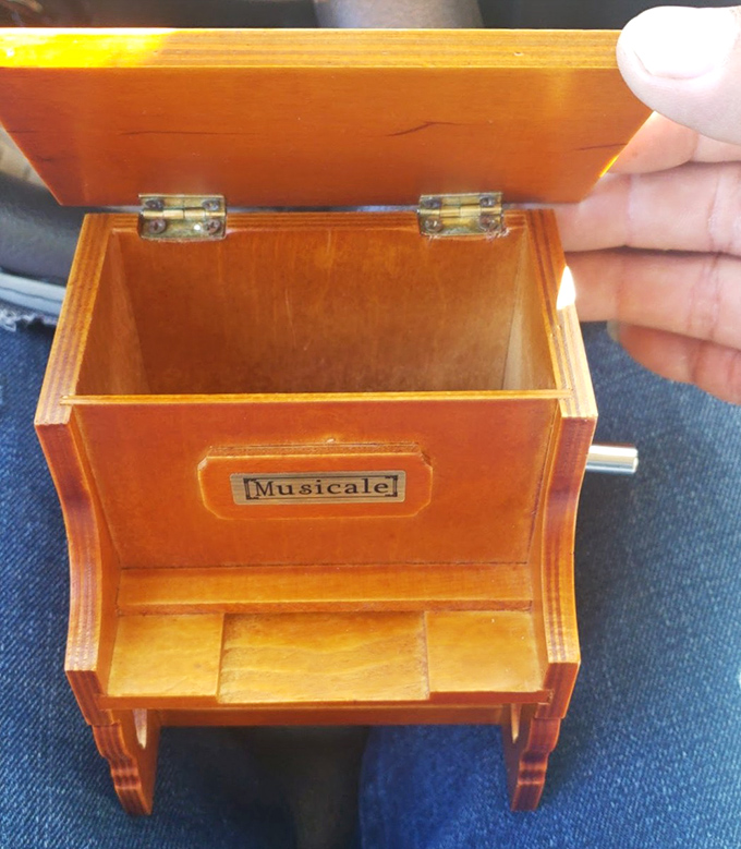 A miniature musical treasure chest that once played lullabies on someone's dresser now waits for its next performance. Nostalgia in wooden form.