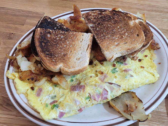 Fluffy eggs embracing ham and vegetables like a warm morning hug, proving that omelets are just pancakes with better personality.
