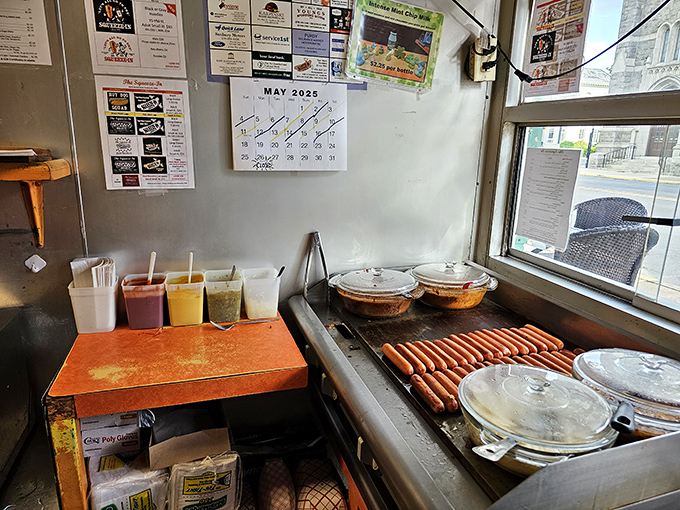 Hot dog artistry in action. Those condiment containers stand ready like paint pots in an artist's studio, waiting to create edible masterpieces.
