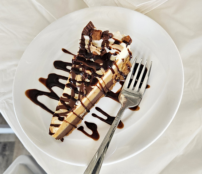 A slice of peanut butter cheesecake that makes sharing seem like a terrible idea. Some desserts are worth the extra mile on tomorrow's walk.