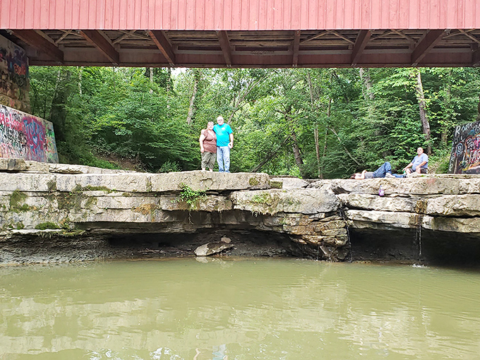 The bridge creates natural gathering spots. Generations have perched on these limestone ledges, dangling feet in the cool water below.
