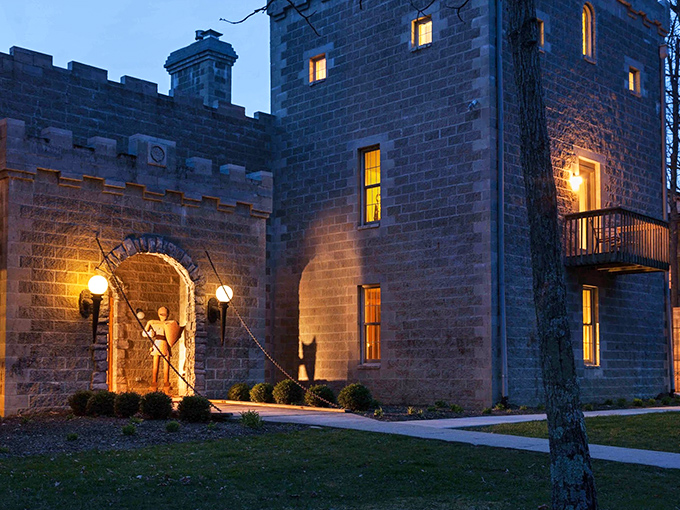 Night casts a spell over Ravenwood Castle, with warm light spilling from windows and illuminating the entrance like a beacon for weary knights.