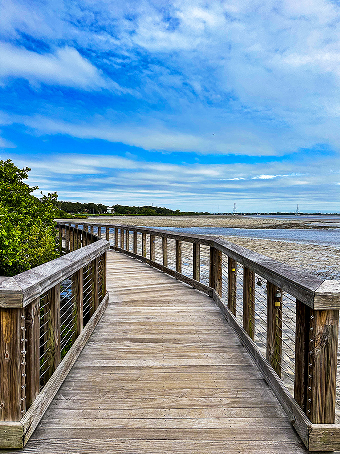 The weathered wooden boardwalk extends like an invitation to explore the natural shoreline, where water and sky perform their daily color-changing magic.