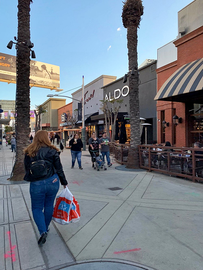 Shoppers wander the palm-lined pathways at dusk, bags in hand, experiencing the post-purchase glow that only great deals provide.