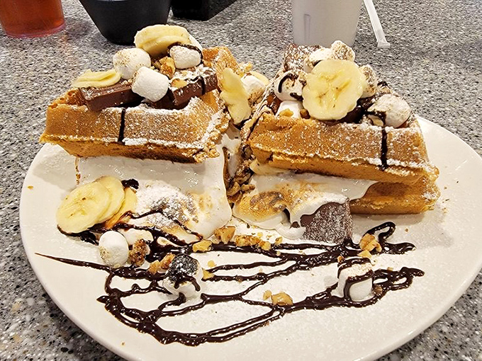 Dessert disguised as breakfast: Belgian waffles transformed into a s'mores fantasy with chocolate, marshmallows, and banana slices that would make campers weep with joy.