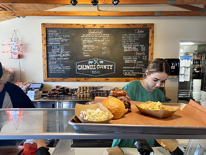 The chalkboard menu behind the counter promises meaty treasures while staff prepare to make your BBQ dreams come true.