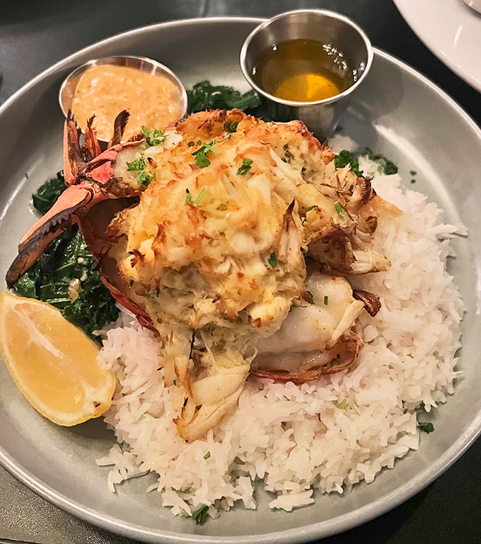 A stuffed lobster tail perched majestically on rice like Neptune's crown jewel, ready for its butter bath.