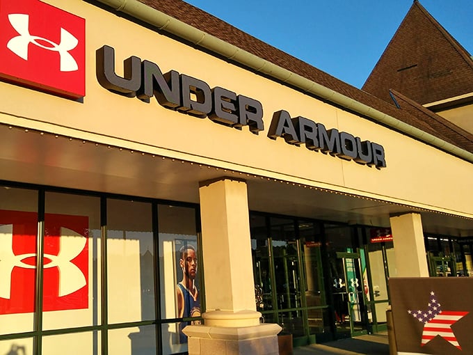 Under Armour's bold signage glows in the evening light, promising performance gear that makes you look athletic even when you're just hunting for deals.