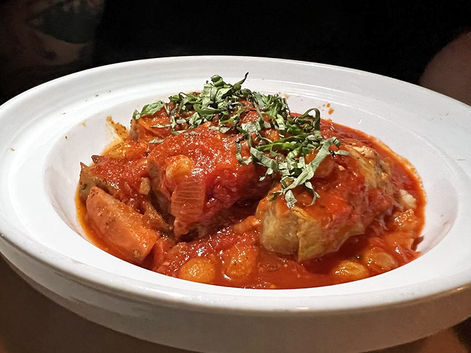 A tomato-based dish that cradles tender meat, the bright sauce and fresh herbs creating a symphony of flavors that dance across your palate.