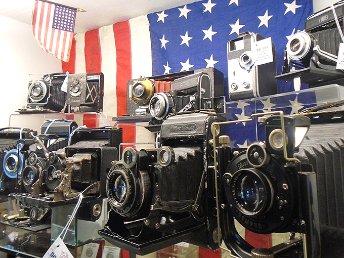 Vintage cameras displayed against an American flag backdrop, capturing both American ingenuity and our enduring desire to preserve memories.