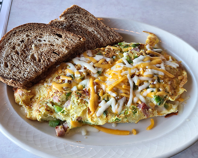 This isn't just an omelet—it's a cheese-blanketed masterpiece that makes breakfast feel like the main event rather than just the opening act.