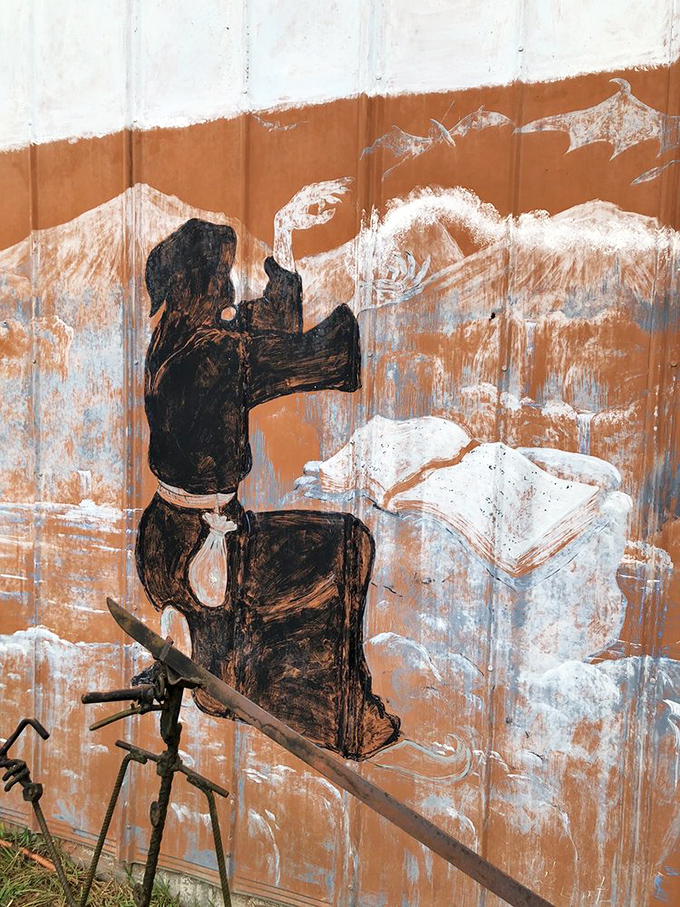 Art emerges from unexpected places&mdash;this painted figure on corrugated metal showcases the castle's commitment to creative repurposing.