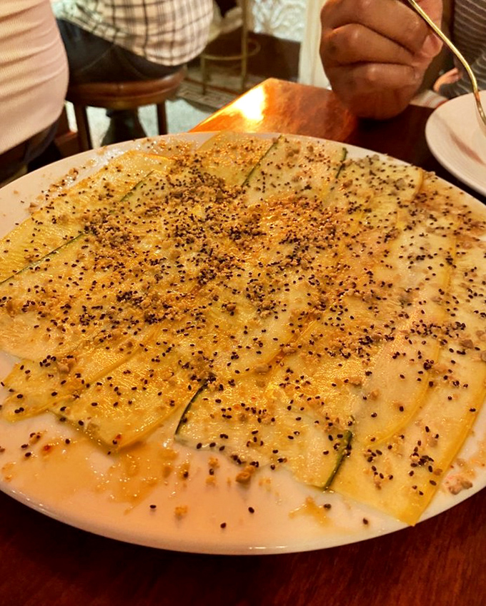 Zucchini carpaccio sprinkled with poppy seeds like stars in a vegetable galaxy. Thinly sliced summer in every bite.
