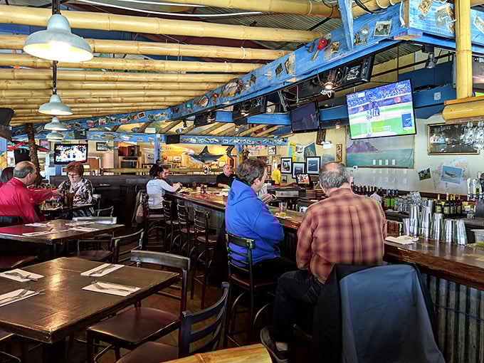 The bar area serves as mission control for thirsty patrons, where aviation enthusiasts swap stories while bartenders orchestrate perfect pours beneath a squadron of model aircraft.