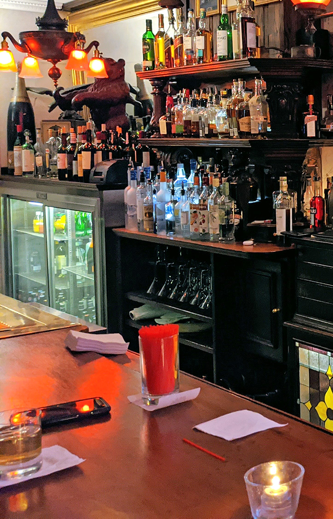 A bar stocked like a museum of liquid happiness. The warm lighting makes every bottle look like it contains the secret to a perfect evening.