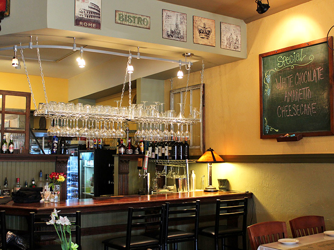 The bar area gleams with promise, wine glasses hanging like crystal stalactites ready to catch whatever magic flows from those bottles.