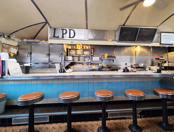 Kitchen choreography at its finest. The compact cooking space behind the blue-tiled counter proves you don't need fancy equipment to create memorable meals.