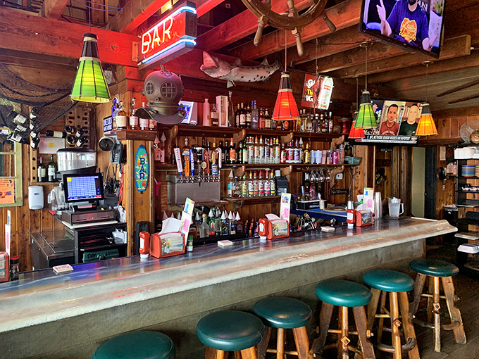 The bar glows with neon promise, where colorful lamps hang like tropical fruits and every stool tells a story of good times past.