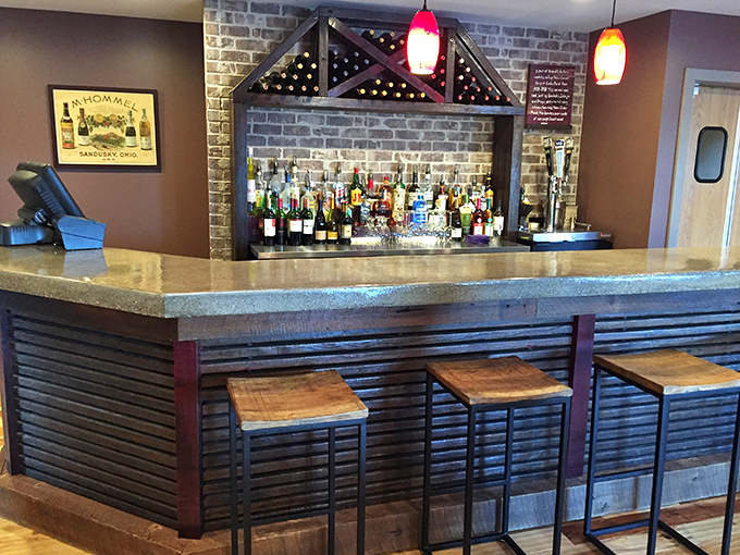 A bar area that whispers "stay for one more" with its warm wood tones and perfectly spaced stools. Wine bottles standing at attention, ready for duty.