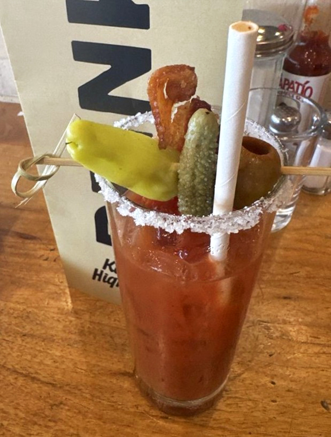 This Bloody Mary isn't just a cocktail; it's a garden party in a glass, complete with a bacon strip VIP and a pickle bouncer.
