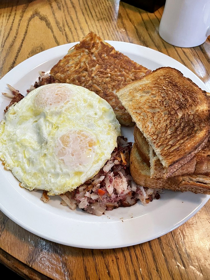 The classic American breakfast trinity: perfectly cooked eggs, crispy hash browns, and toast waiting patiently for its butter bath.
