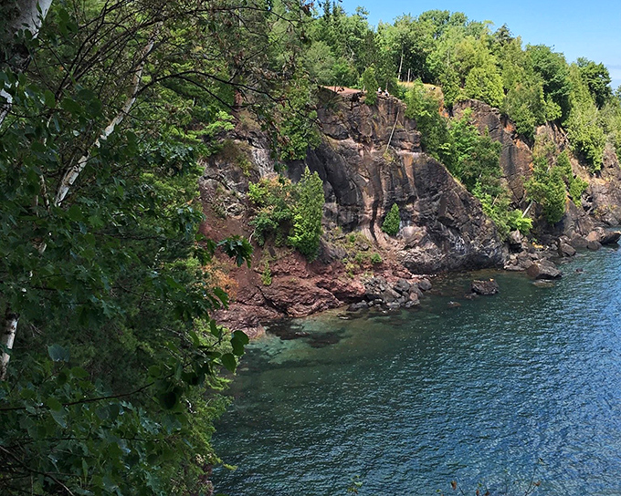 Lake Superior's crystal waters reveal the reddish bedrock below, creating that distinctive shoreline palette unique to Michigan's Upper Peninsula.