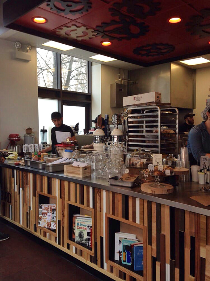 Behind the counter, where the magic happens. Those wooden panels holding cookbooks like sacred texts, each one a potential source of the next great menu item.