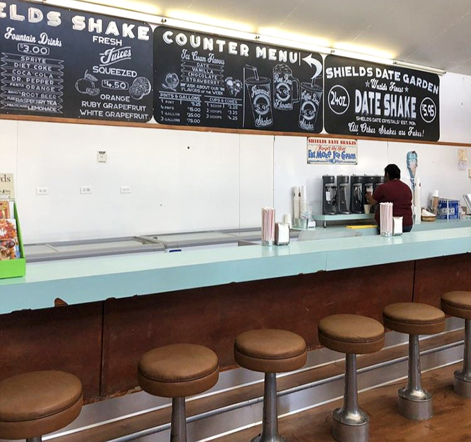 Classic counter seating beneath a chalkboard menu promises date shakes and fountain treats&mdash;a nostalgic nod to simpler, sweeter times.