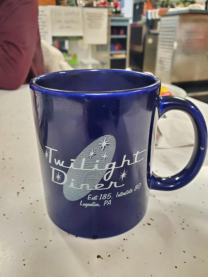 The iconic blue Twilight Diner mug &ndash; a collector's item for regulars and a beacon of hope for the caffeine-deprived traveler.