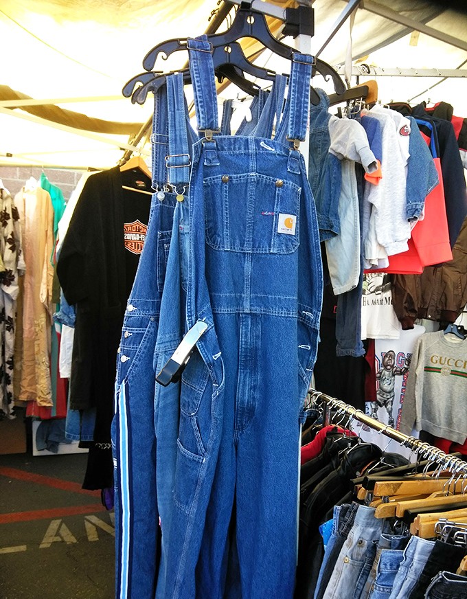 Classic Carhartt overalls hanging proudly among vintage threads&mdash;the uniform of America's working class now coveted by fashion-forward urbanites and authentic laborers alike.