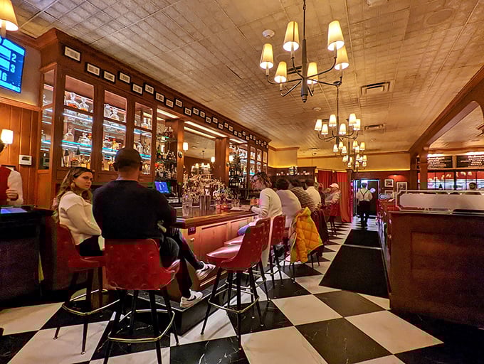 The bar area hums with energy as patrons perch on those tufted red stools, plotting their attack on both cocktails and steaks.