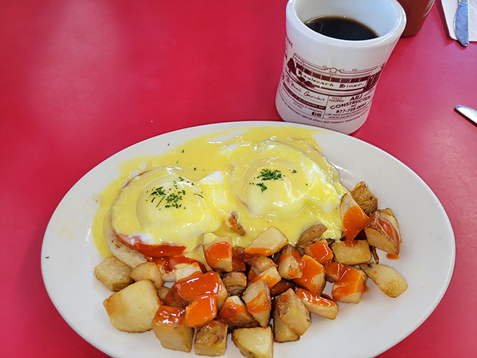 Eggs Benedict done diner-style &ndash; hollandaise cascading over English muffins alongside those famous home fries, breakfast elevated without any pretension.