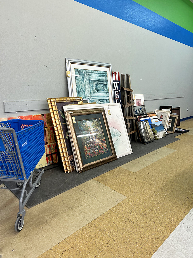 The wall of forgotten masterpieces. Gold frames and landscape prints lean casually, as if in an eccentric gallery's back room.