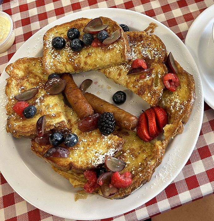 French toast that transforms ordinary bread into something magical, adorned with fresh berries and a dusting of powdered sugar. Breakfast or dessert? Yes.
