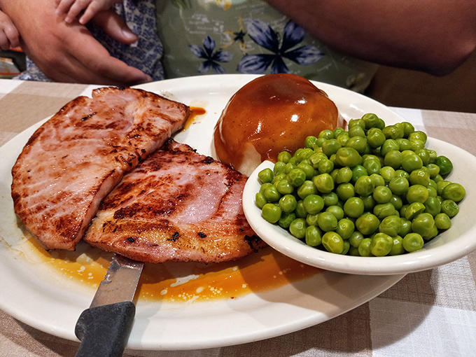 Ham steaks glistening with glaze, peas so green they could stop traffic, and a dinner roll that's basically a pillow made of butter and flour.