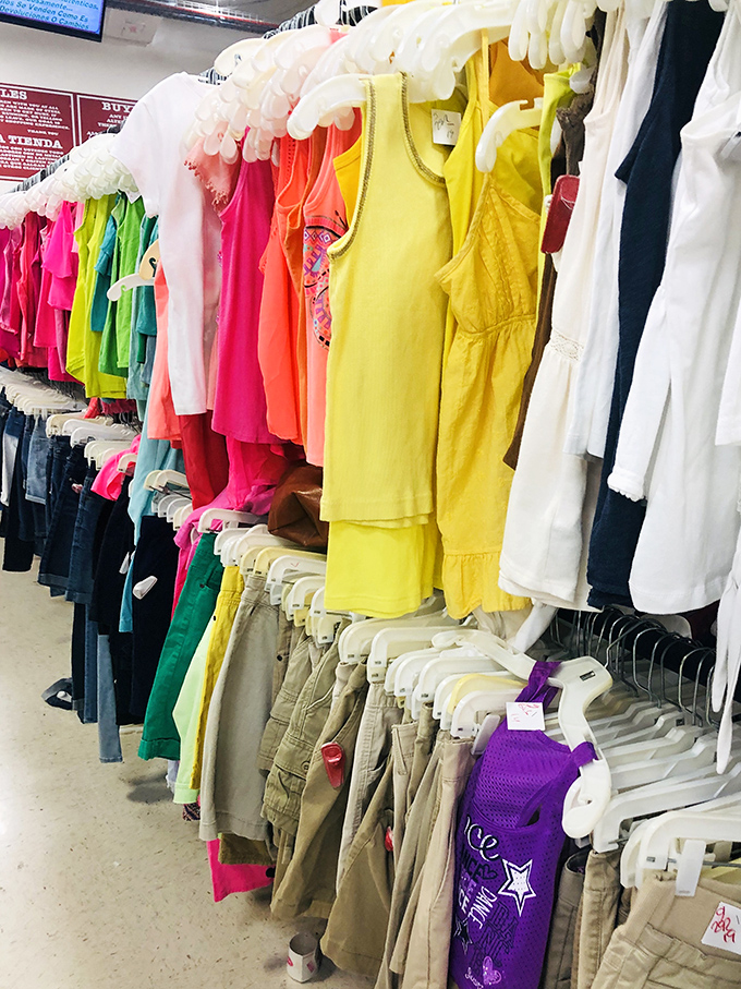 A rainbow of children's clothes, arranged by color rather than size—nature's way of making parents exercise while shopping.