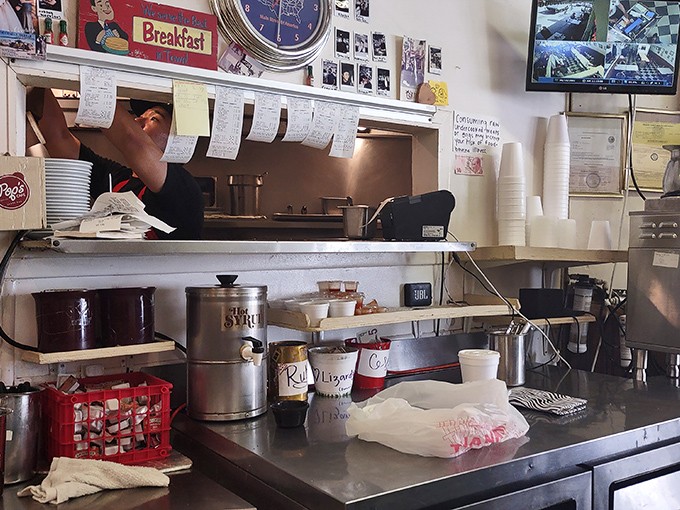 The kitchen pass&mdash;where orders hang like promises and the choreography of short-order cooking unfolds with practiced precision.