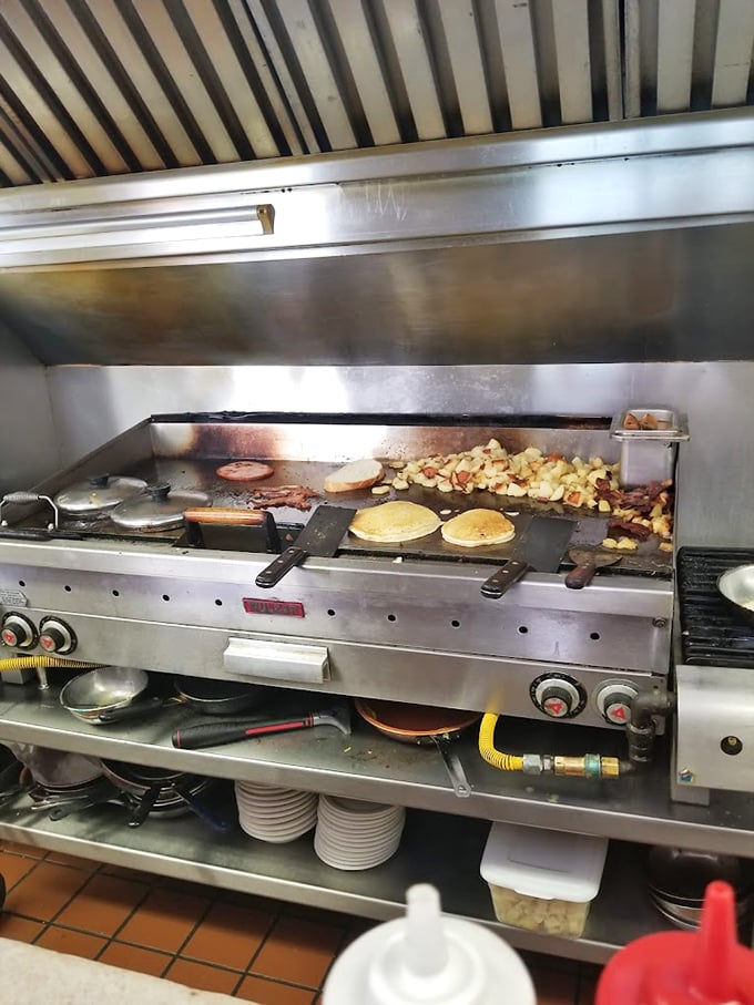 The flattop grill works overtime, transforming simple ingredients into breakfast masterpieces while diners watch the culinary theater unfold before them.