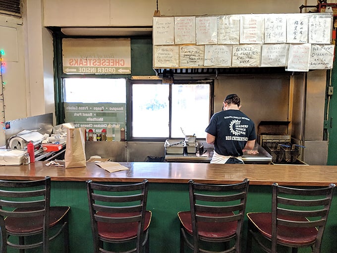 Behind this counter, pizza artisans perform their daily ritual, transforming humble ingredients into slices of perfection.