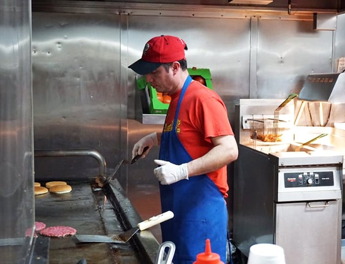 Culinary choreography in action. That focused expression says, "I've flipped more perfect patties than you've had hot meals," and we're all better for it.
