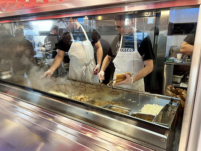 The kitchen crew in their element&mdash;culinary conductors orchestrating a symphony of sizzling meat and melting cheese behind the glass.