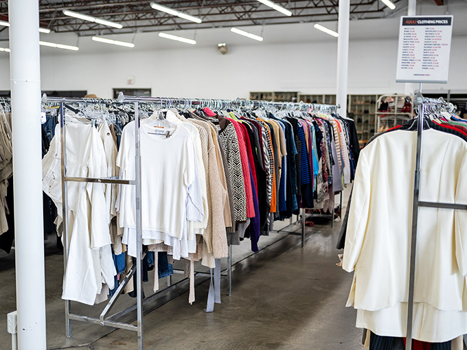 Clothing racks organized by color create a rainbow road of possibilities, where vintage meets modern in a fashion democracy of affordability.