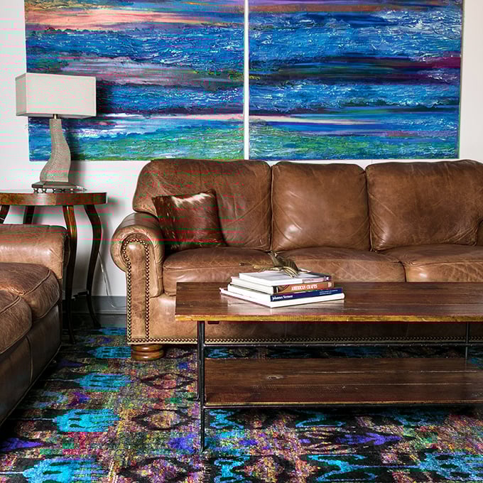Rich leather sofas beneath vibrant abstract art create the perfect tension between traditional comfort and contemporary visual excitement.