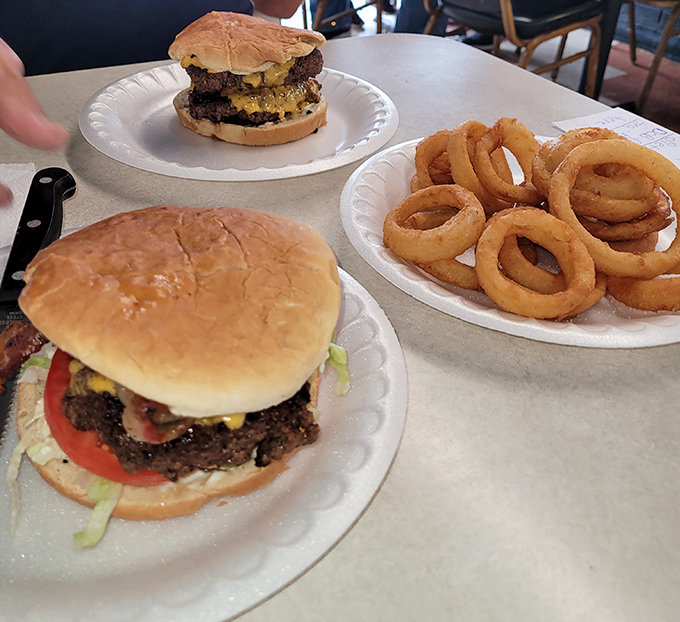 Burgers commanding the foreground while onion rings wait patiently for their moment of glory. A study in circular food perfection.