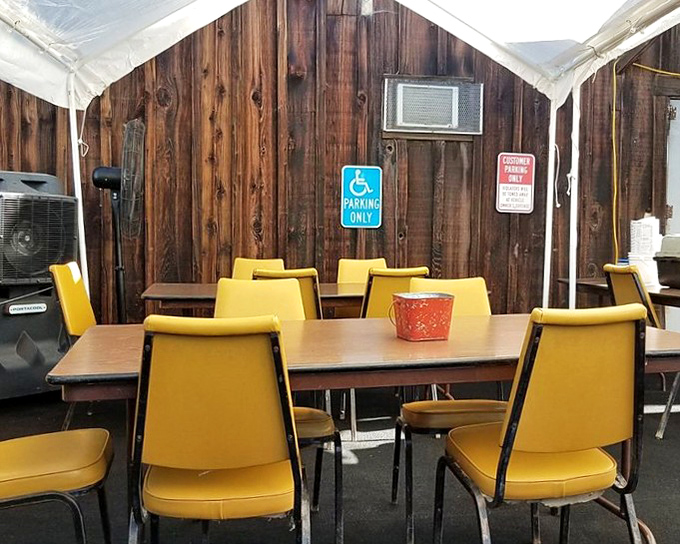 Yellow chairs against rustic wood paneling create an outdoor dining space that feels like eating at a friend's cabin &ndash; if your friend were an excellent cook.